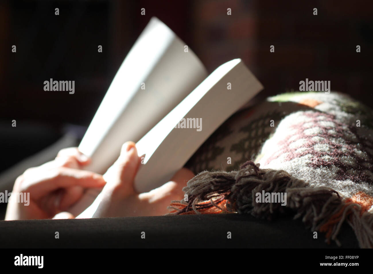 A person reading a book, surrounded by a cozy environment with an open ...