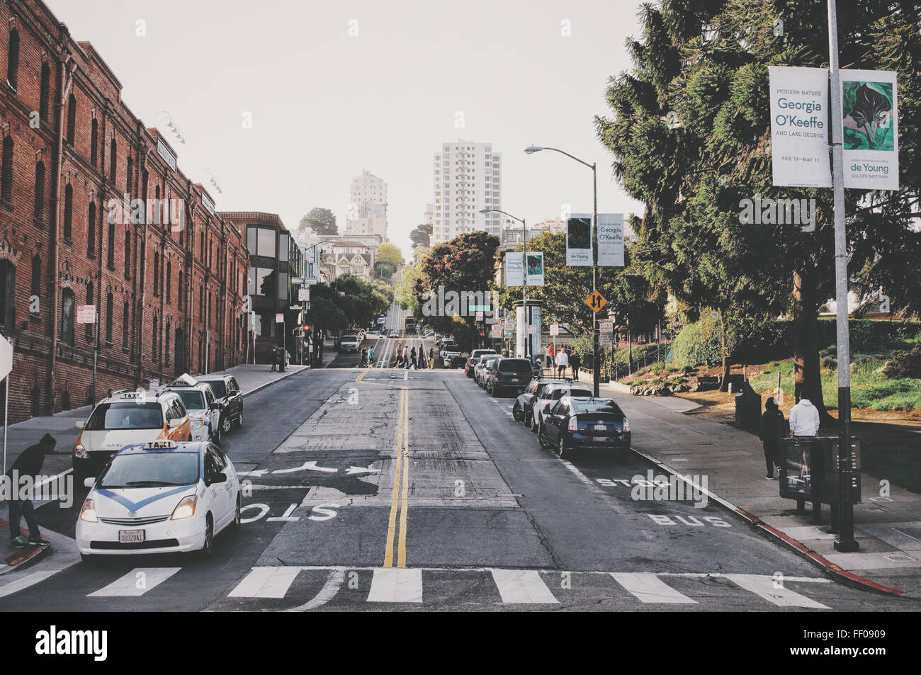 A city intersection with crosswalks and streetlights. A taxi passes by ...