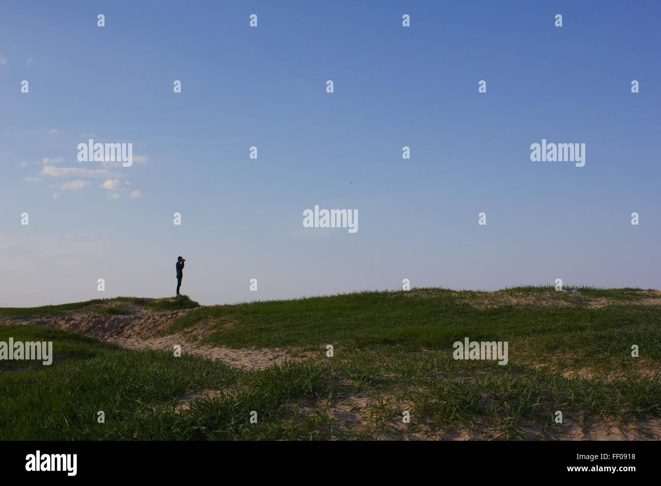 A solitary person stands on a vast, empty landscape, emphasizing ...
