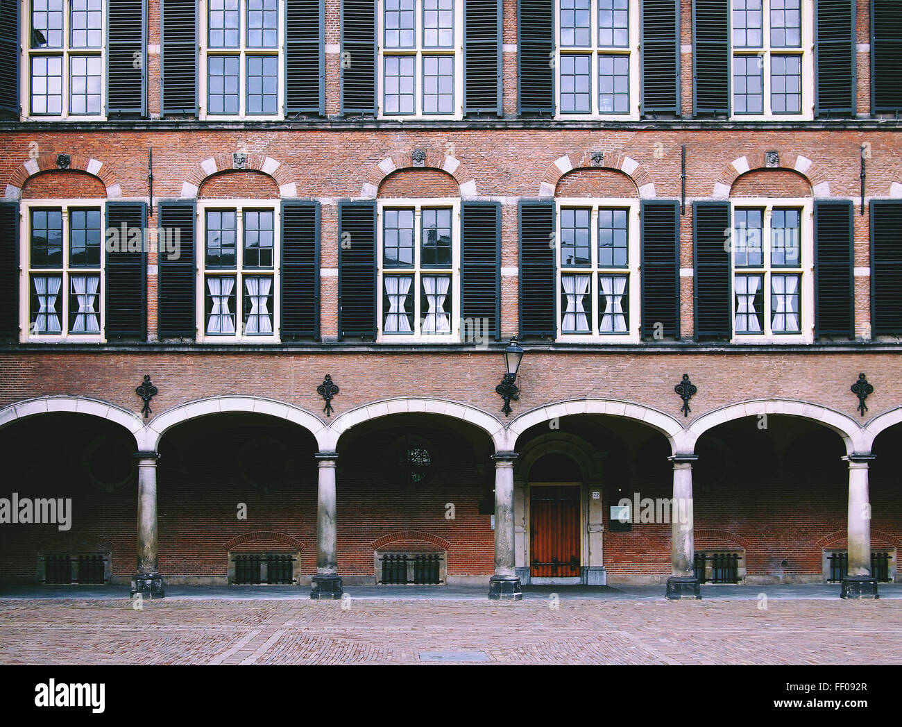 This image depicts a set of windows in a brick courtyard, framed by ...