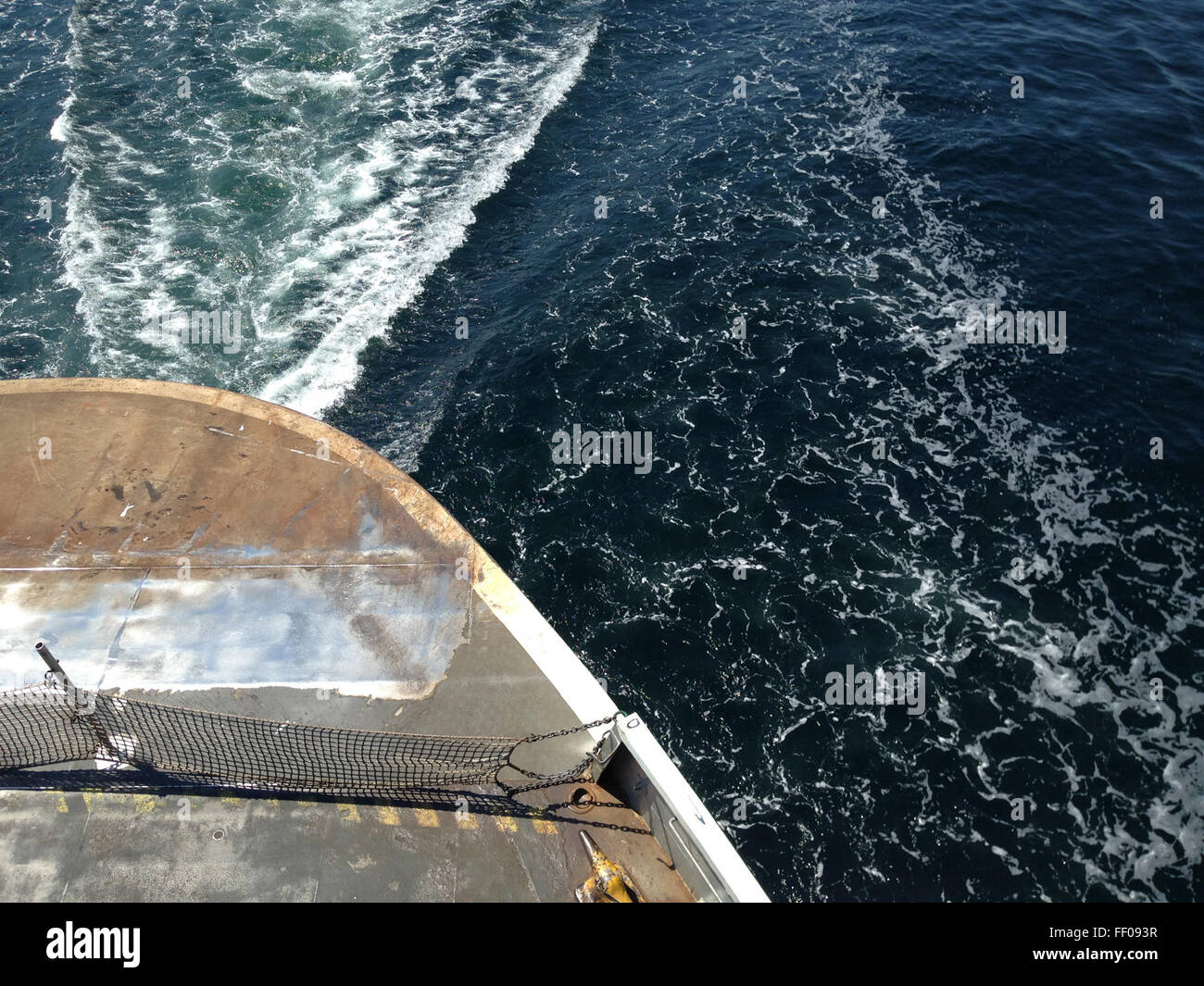 The wake in the ocean water behind a ship shows the turbulent effect of ...