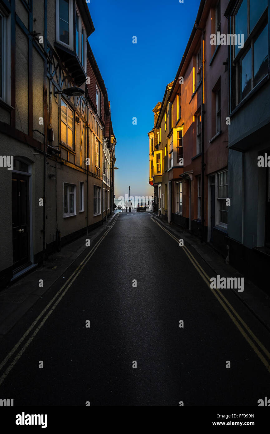 A narrow lane between buildings at sunset creates a dramatic urban ...