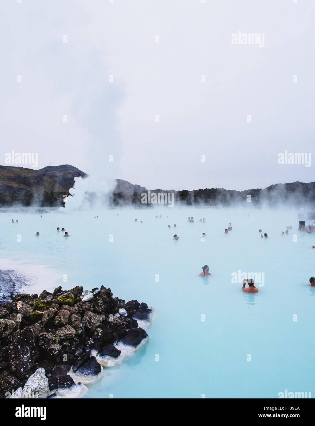 A group of people relaxes in a geothermal hot spring, enjoying the ...