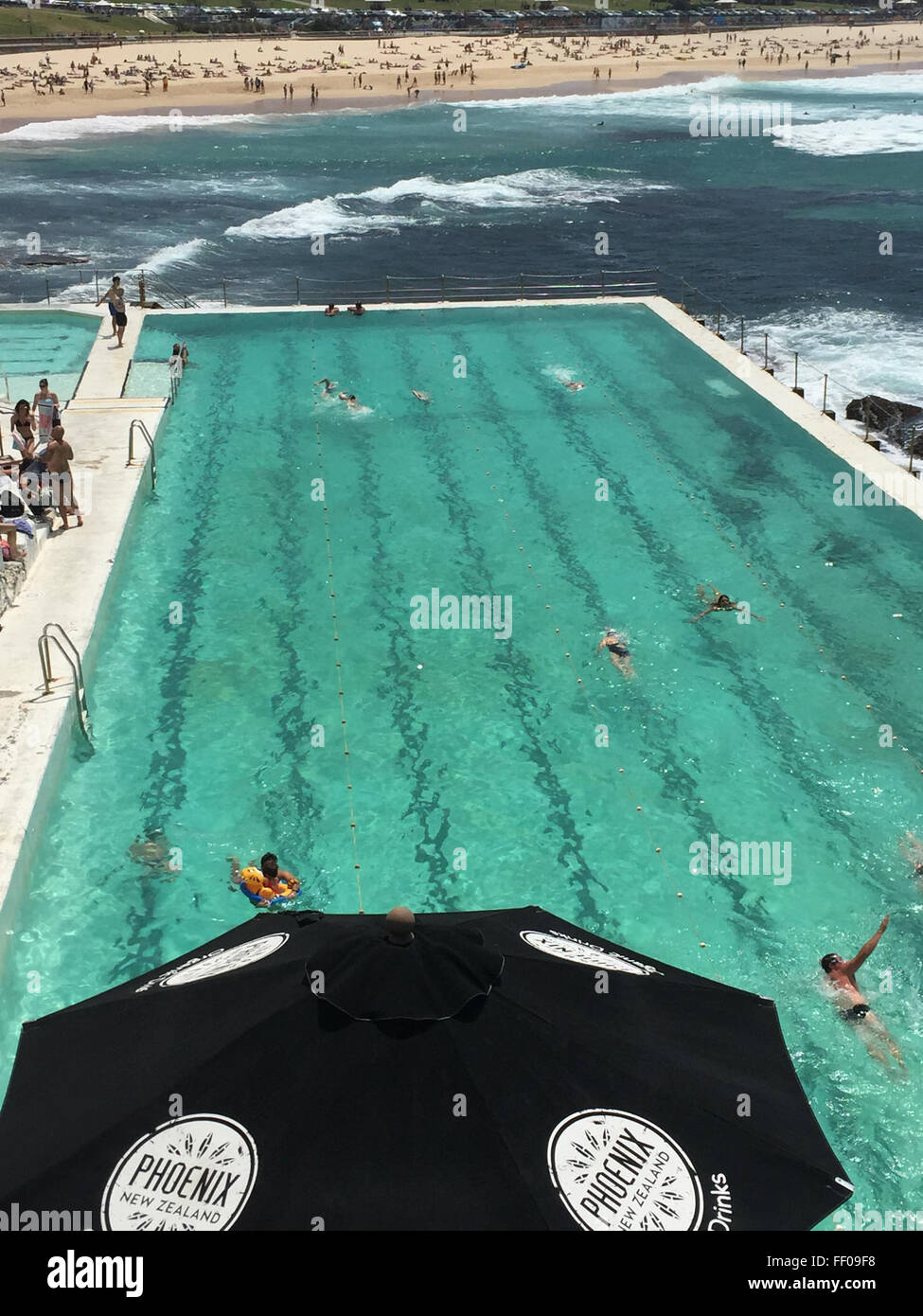 A resort pool located by the beach, with people swimming in the clear ...