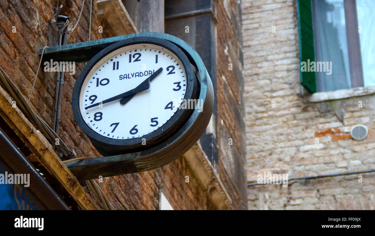 A large clock mounted on the side of a brick building, serving as both ...