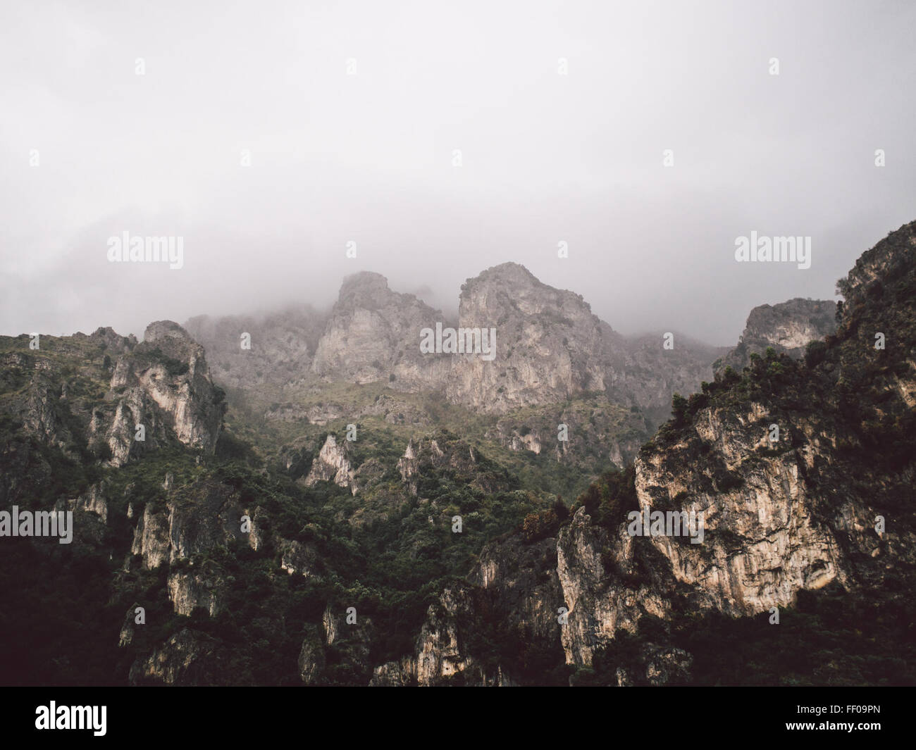 The scenic mountains are partially shrouded in fog, creating a ...