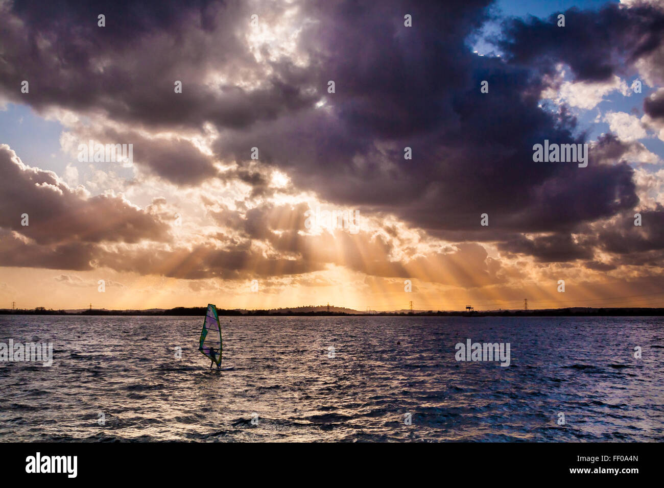 A windsurfer takes the last tack of the day against a backdrop of ocean ...