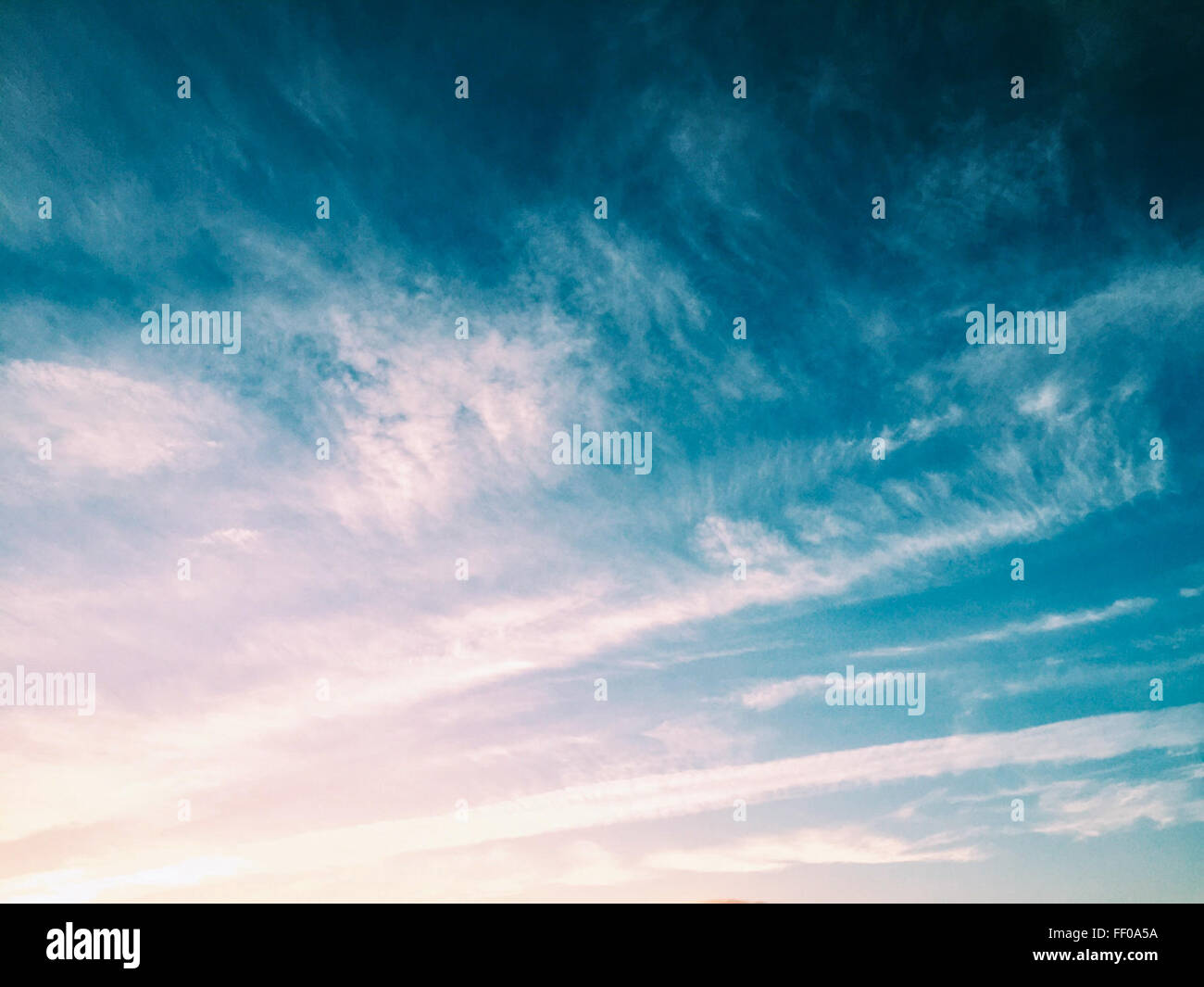 Wispy cirrus clouds stretch across a blue sky, forming delicate ...