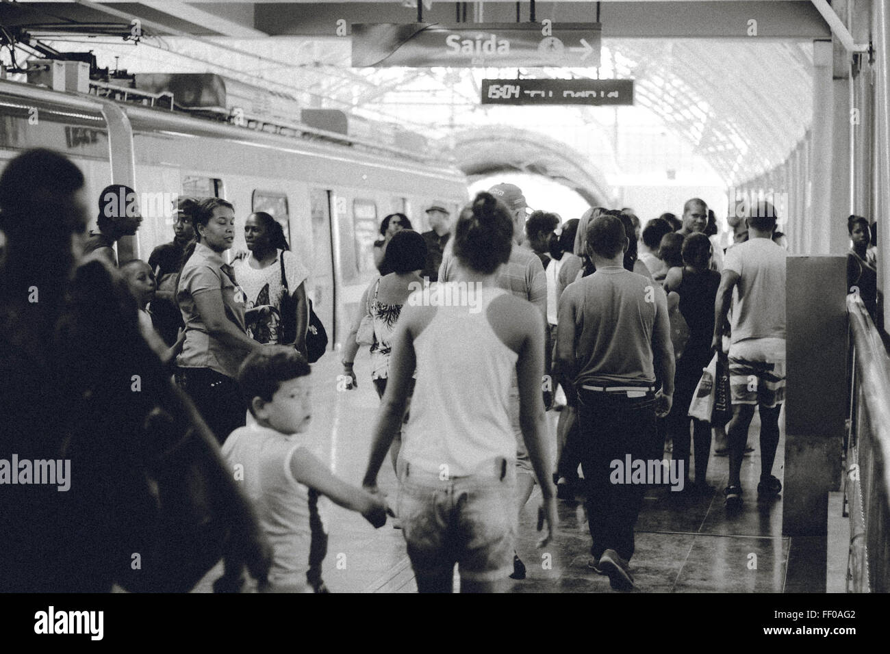 A crowded rail station filled with commuters waiting to board trains ...