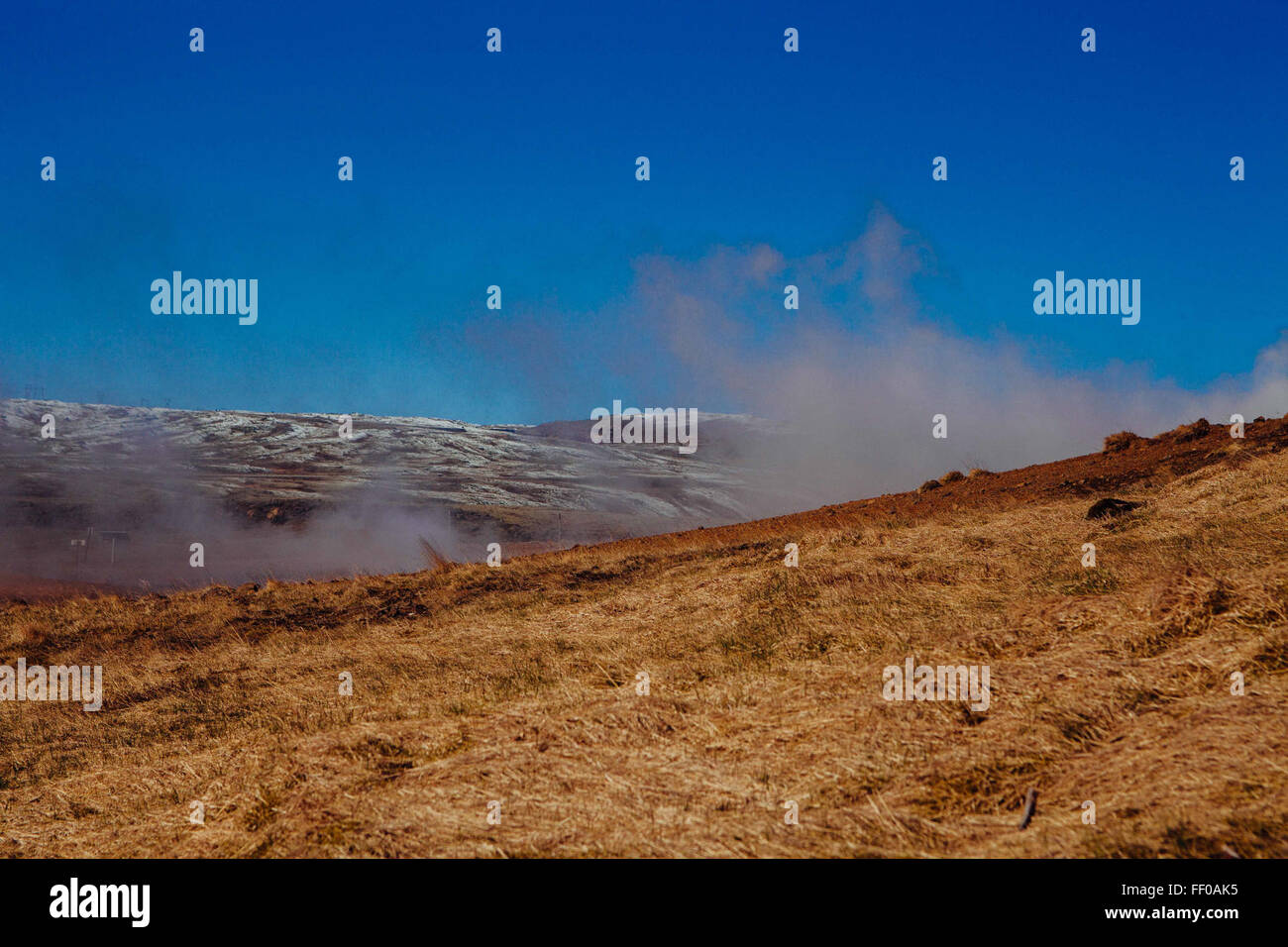 A dry field with smoking grass, likely due to a fire or intense heat ...