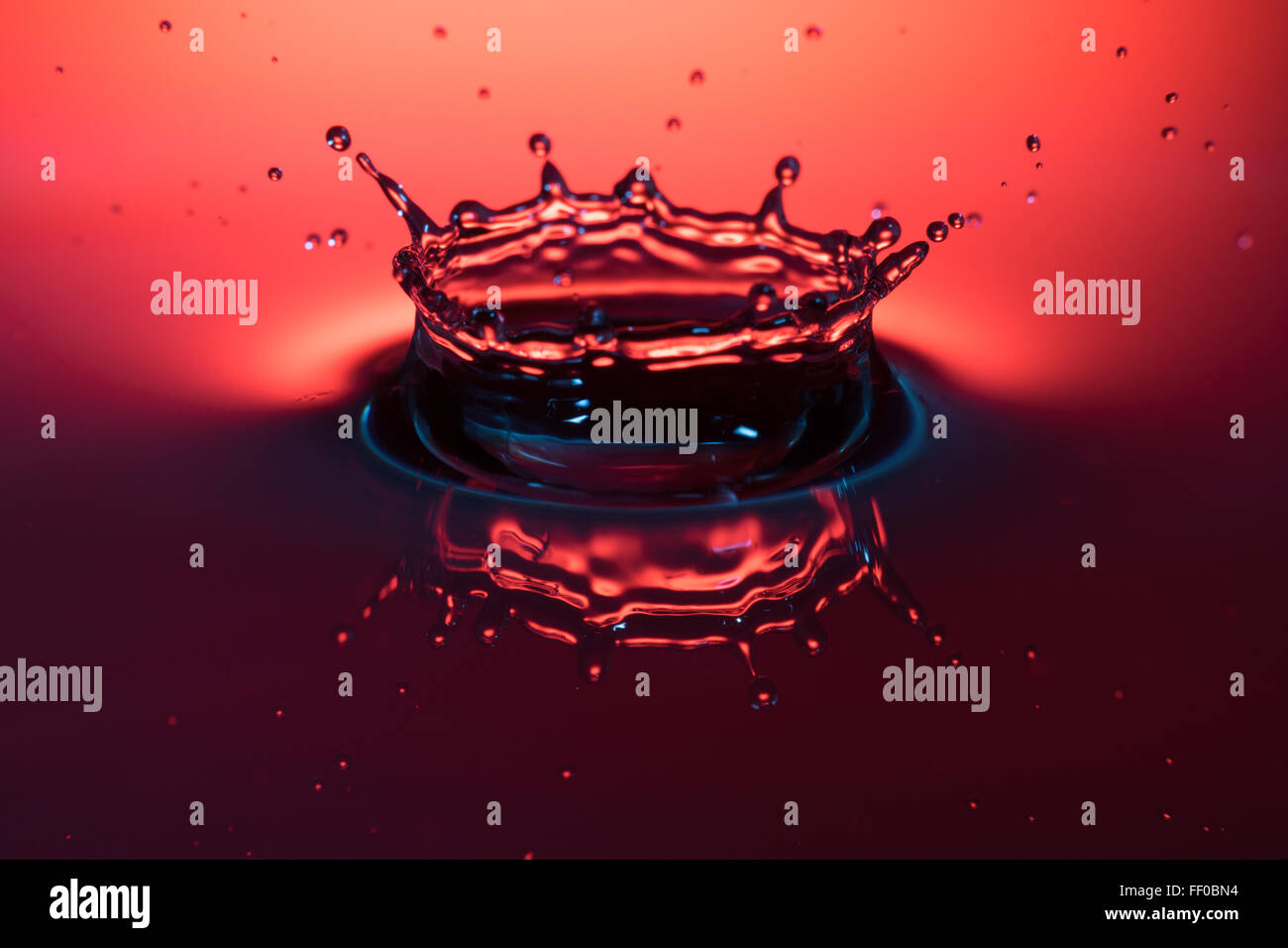 A drop of water hitting the surface of a container full of liquid Stock ...