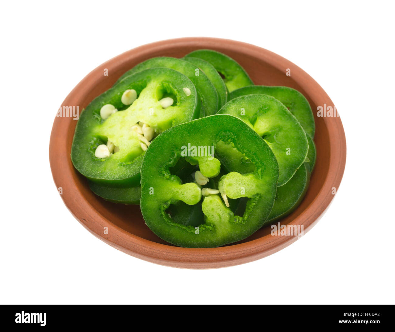 A small bowl of sliced jalapeño peppers isolated on a white background ...