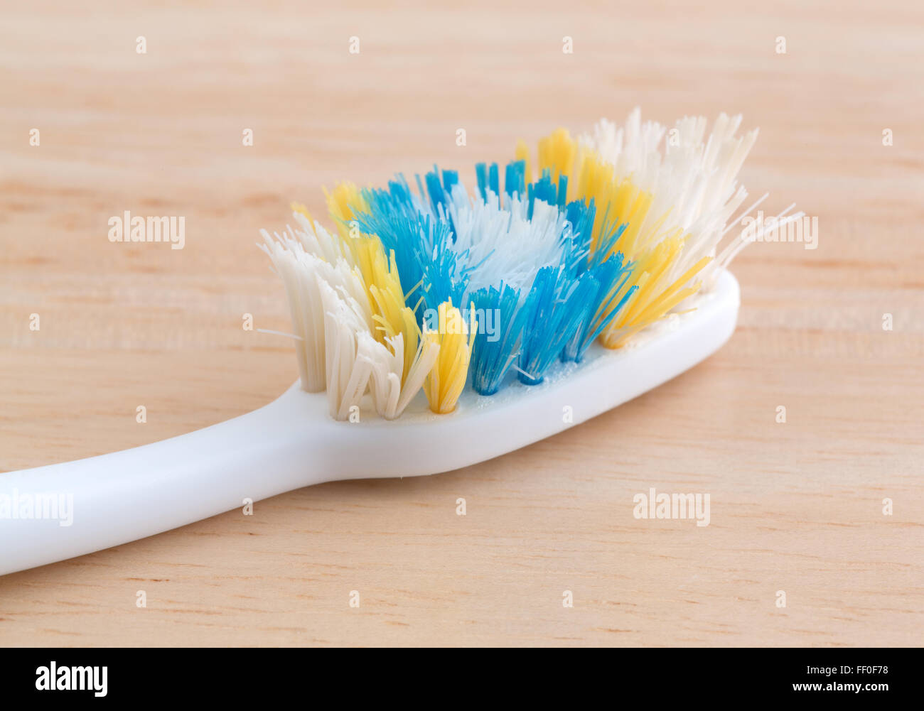 An old worn toothbrush with bent bristles on a wood counter top ...