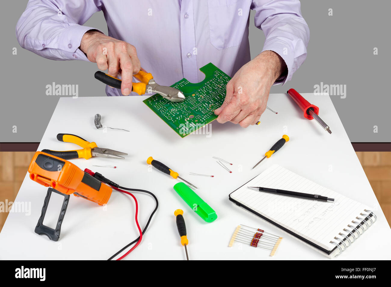 Electronic test engineer using side cutters to trim a soldered ...
