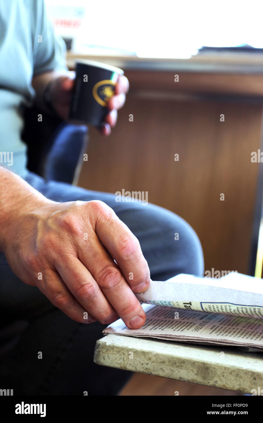 Adult Caucasian male Flipping newspaper while having a cup of hot drink ...