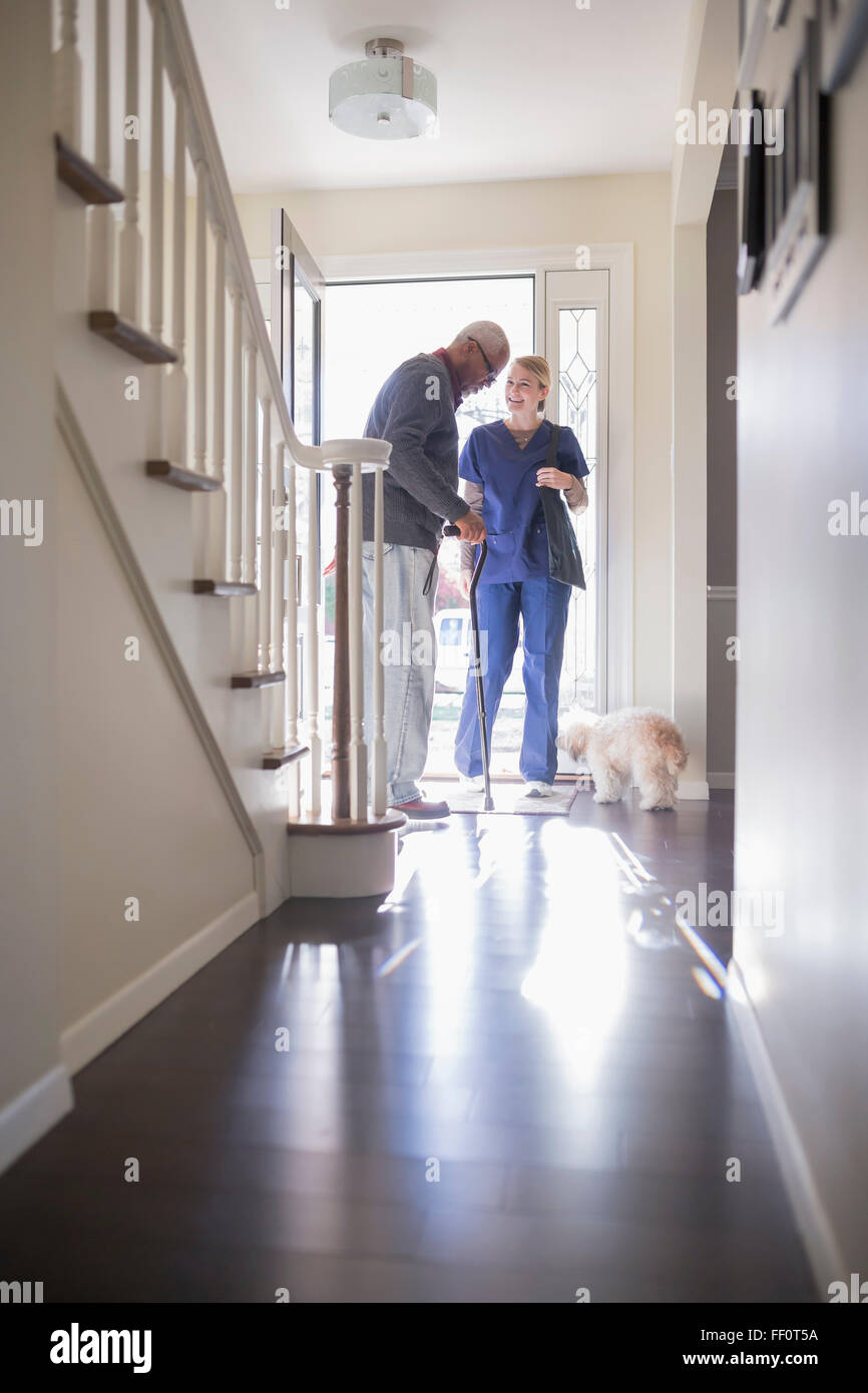 Nurse helping patient walk with cane Stock Photo - Alamy