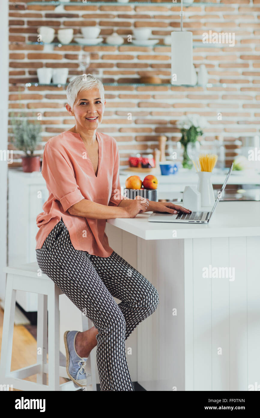 Older Caucasian woman using laptop in kitchen Stock Photo - Alamy