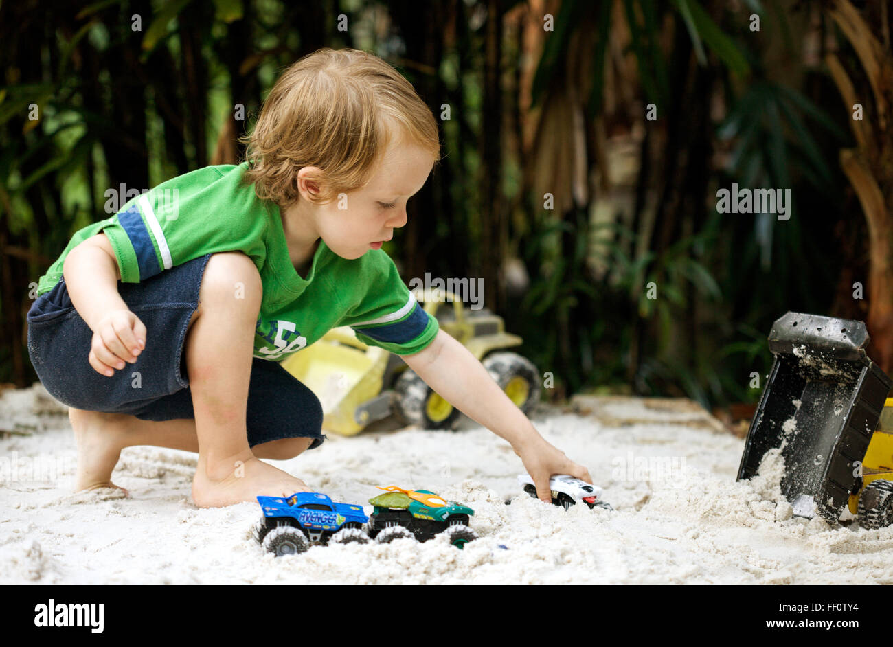 A young boy plays with trucks in a sandbox outdoors Stock Photo - Alamy