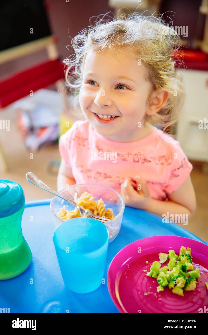 Caucasian girl eating in high chair Stock Photo - Alamy