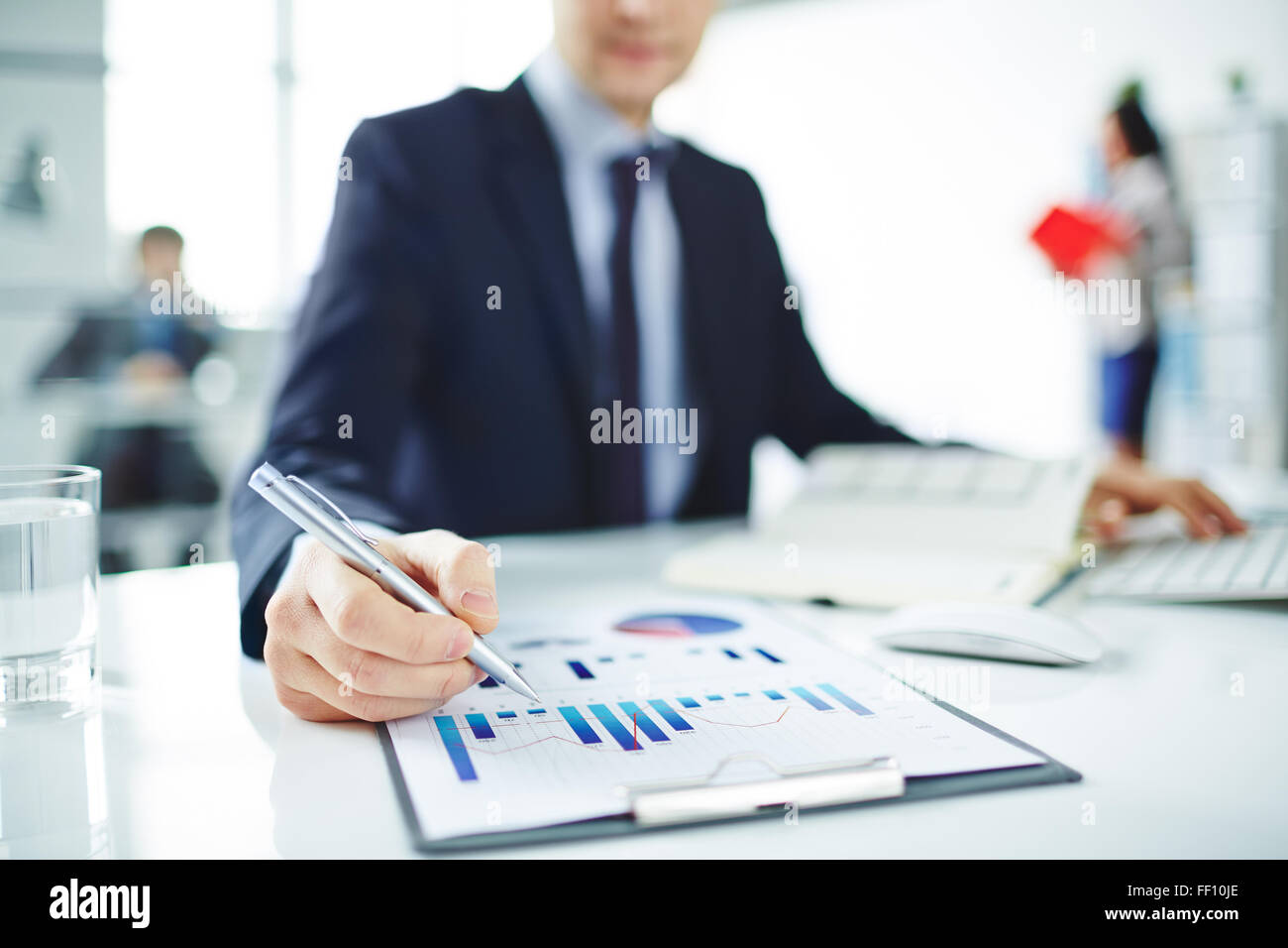 Young businessman pointing at chart in document in office Stock Photo ...