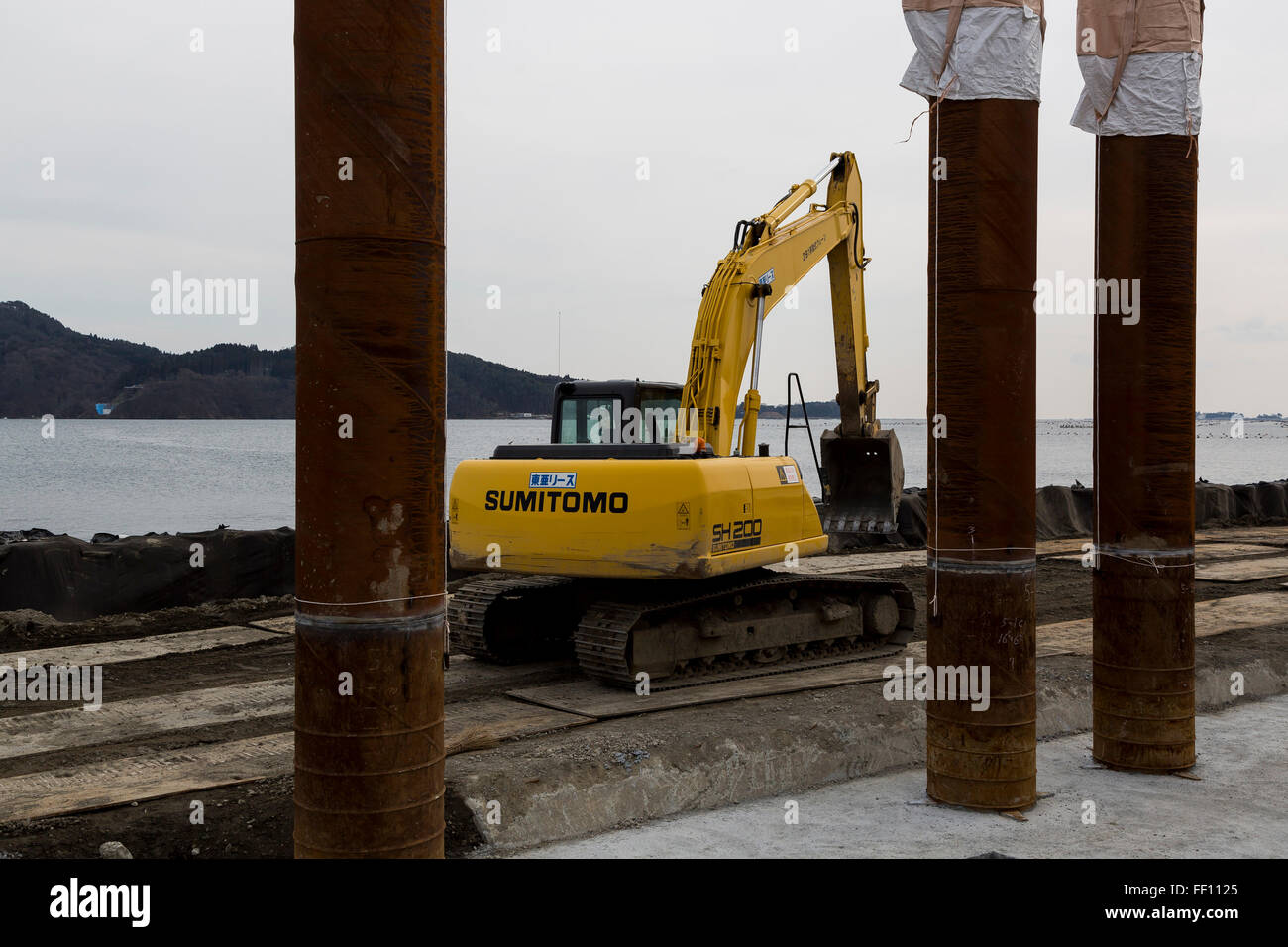 A bulldozer works in the construction of a 1.61 km long tsunami barrier ...