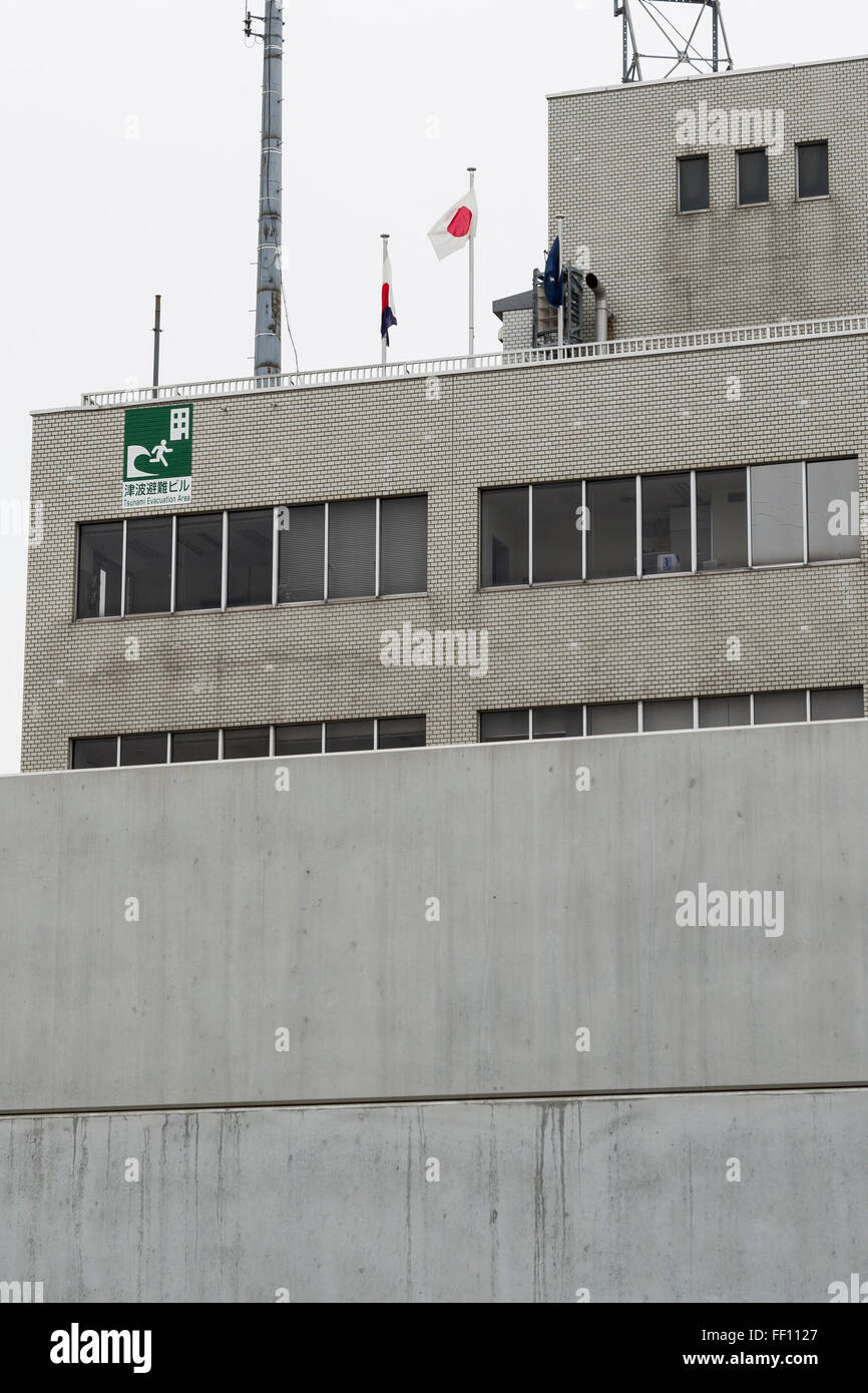 A tsunami evacuation sign on the top floor of a building built behind a ...
