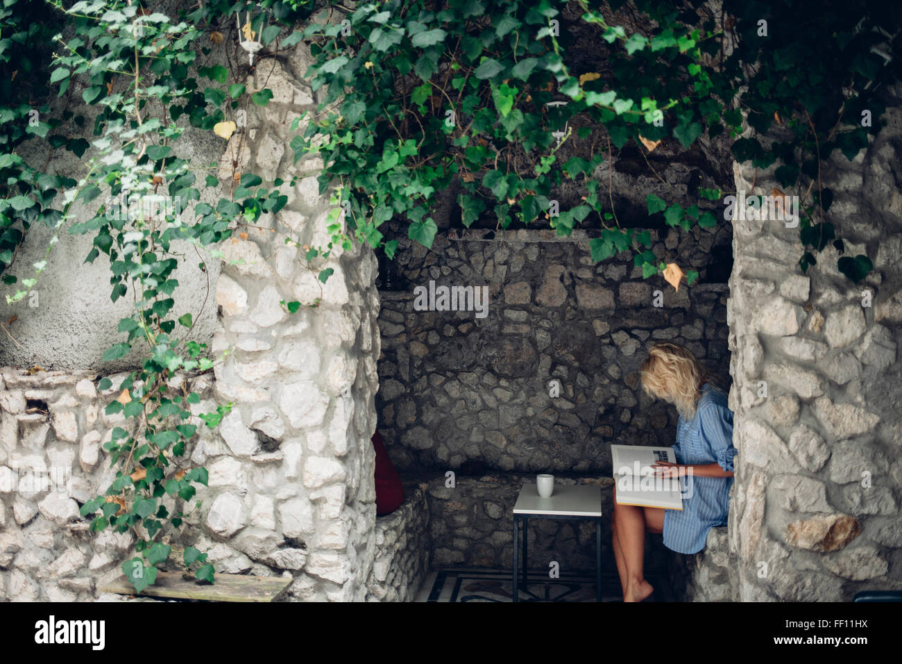 Woman sitting in stone patio Stock Photo - Alamy