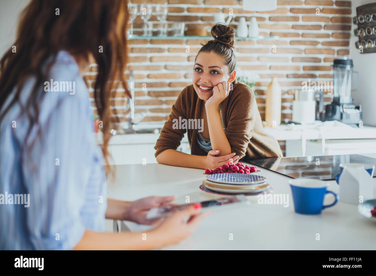 Caucasian women talking in kitchen Stock Photo - Alamy