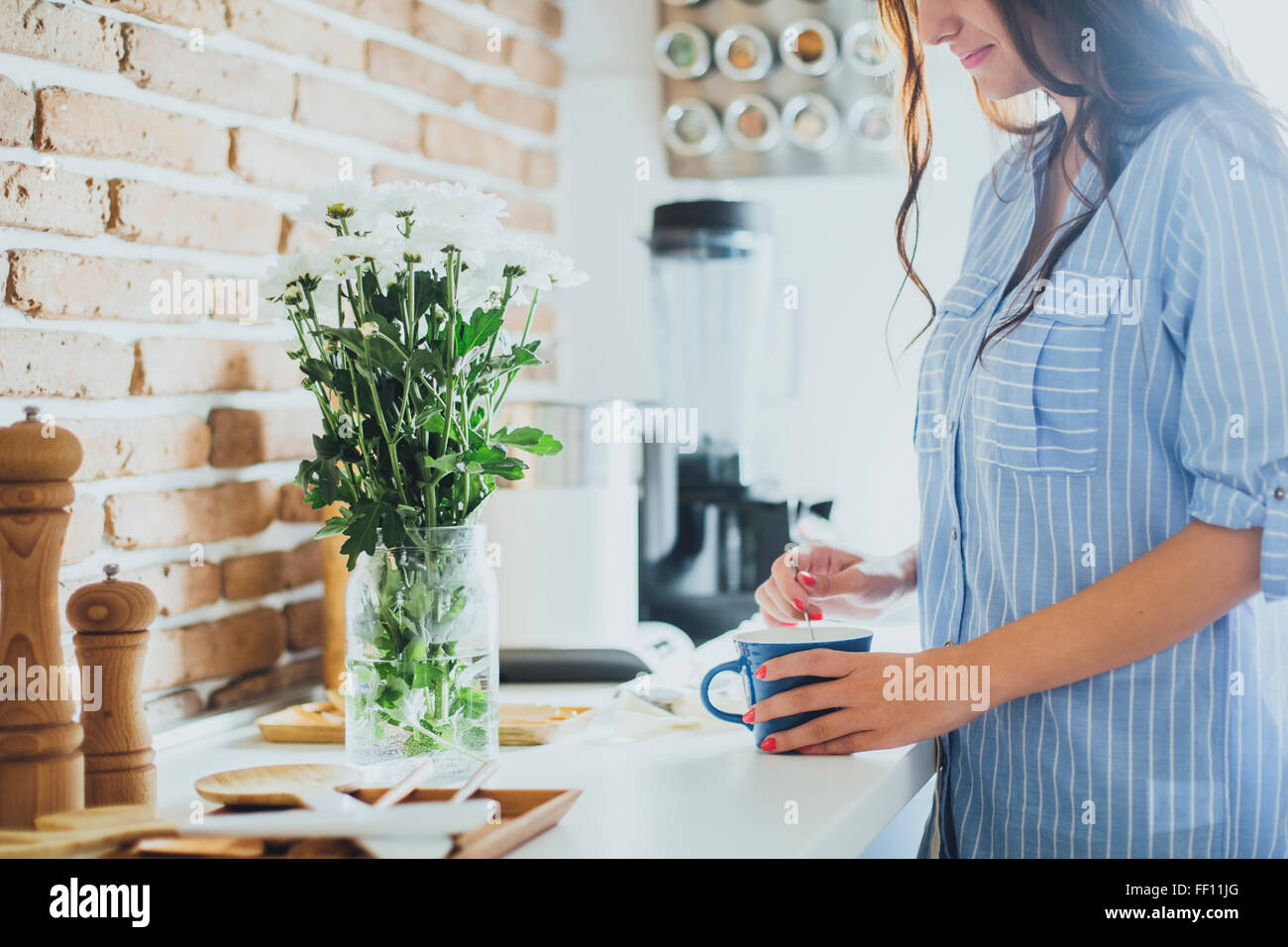 Caucasian woman stirring coffee in kitchen Stock Photo - Alamy