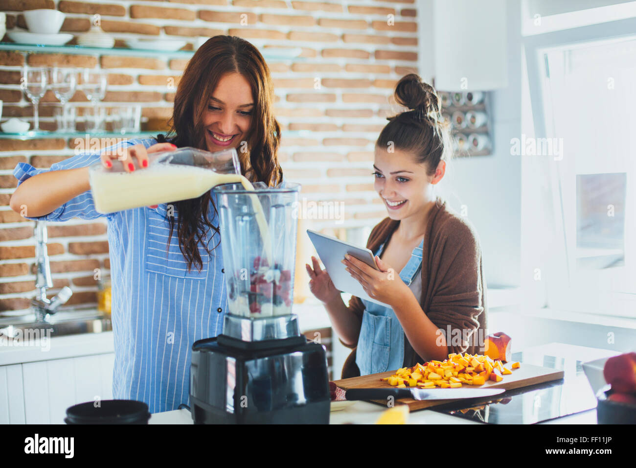 Caucasian women making smoothie in kitchen Stock Photo - Alamy