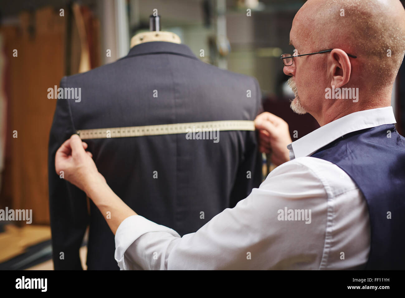 Mature tailor measuring back of jacket at work Stock Photo - Alamy