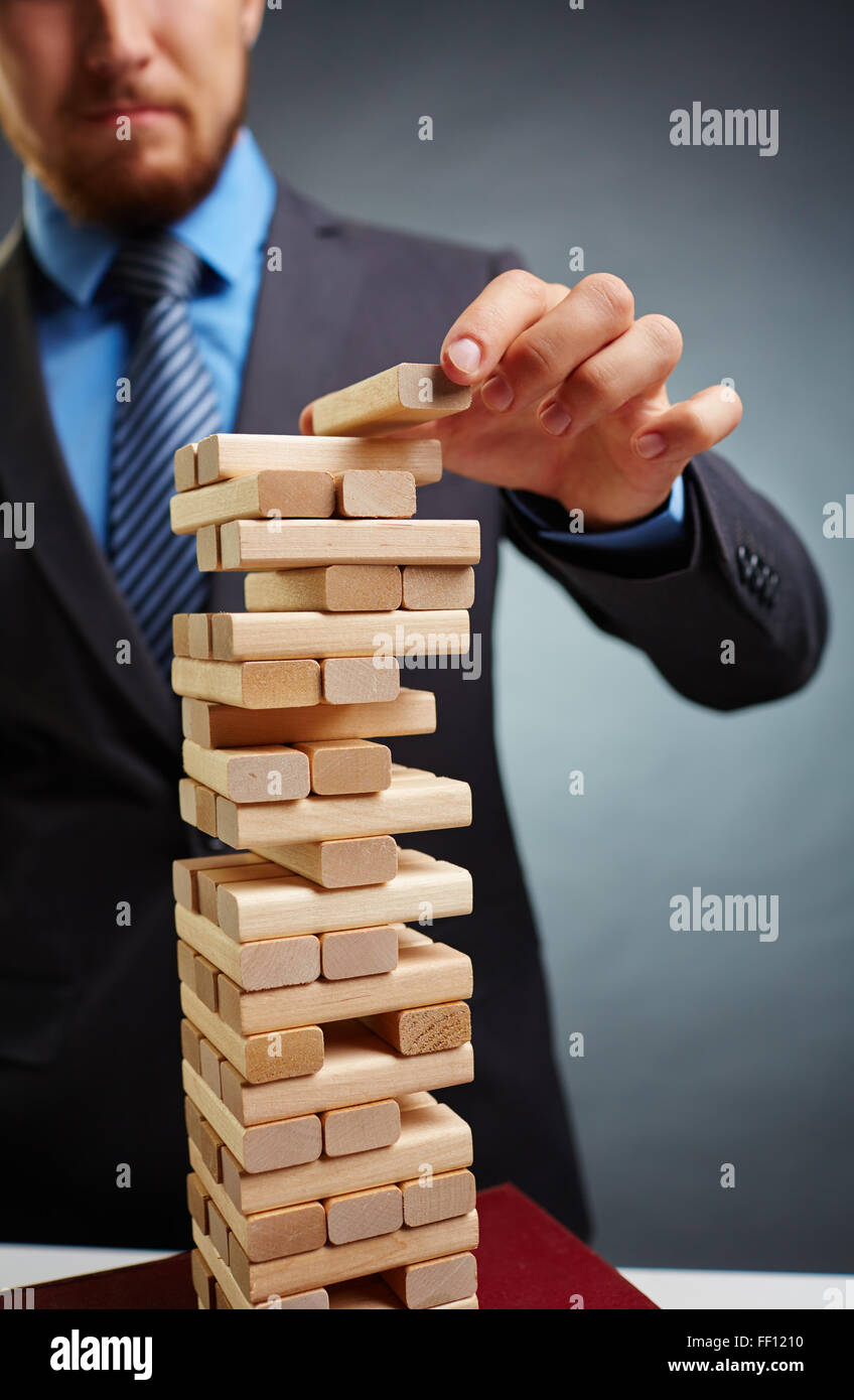 Modern businessman building high tower from small wooden blocks Stock ...