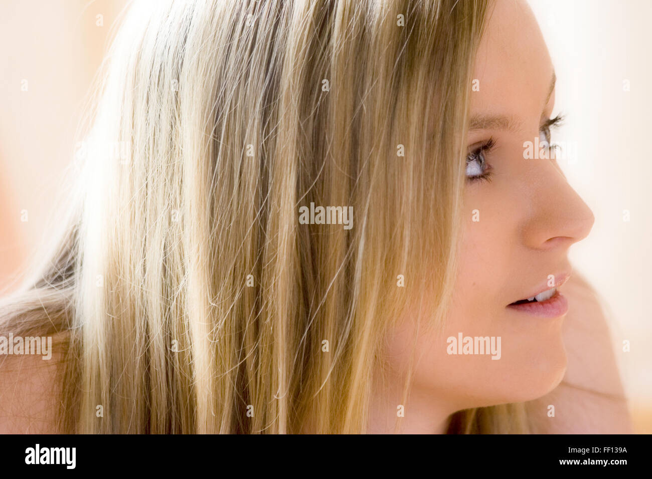 Caucasian blonde blue eyed teenage girl. Side view of face, looking up ...