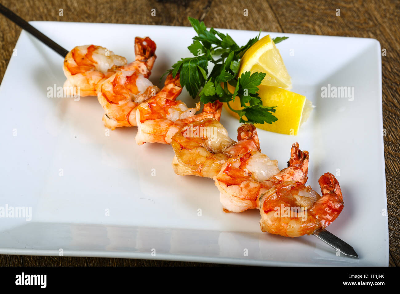 Tiger prawn skewer served sliced lemon and parsley Stock Photo - Alamy