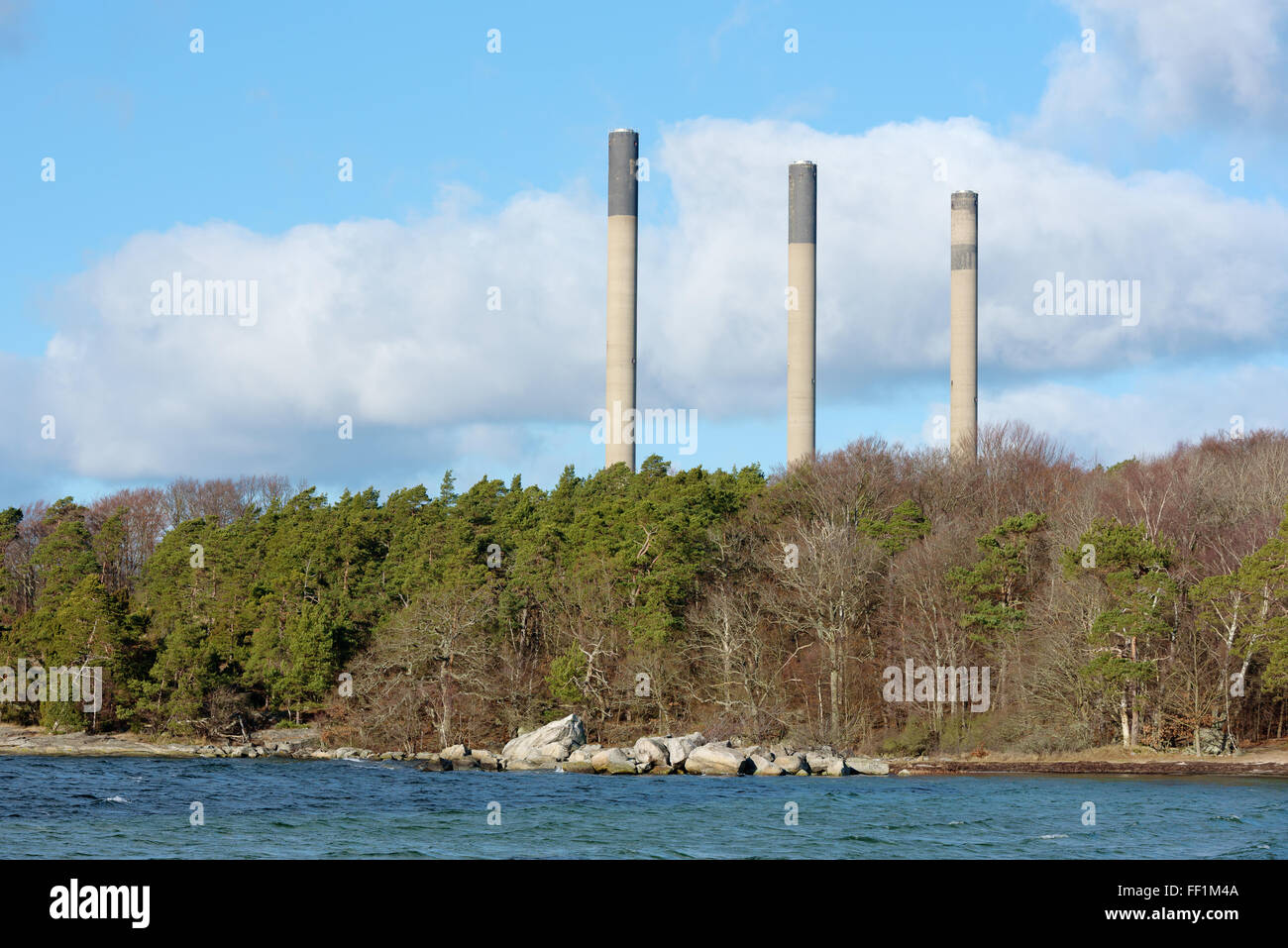 Three chimneys tower above the forest. Clouds in background Stock Photo ...