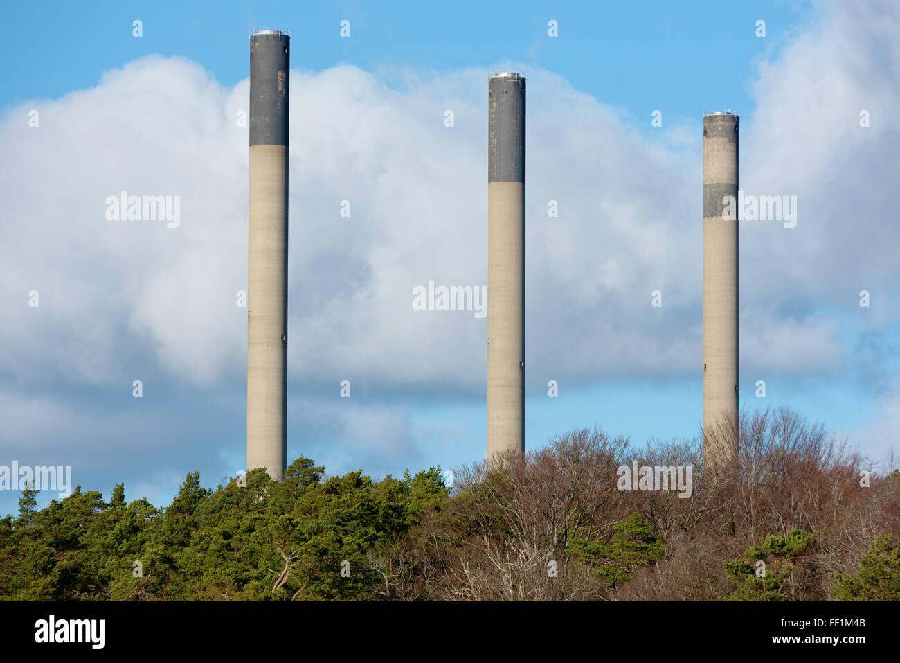Three chimneys tower above the forest. Clouds in background Stock Photo ...