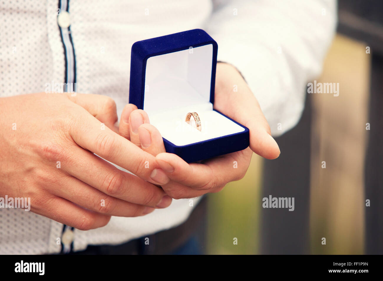 wedding rings in a blue box in a hand at the groom Stock Photo - Alamy