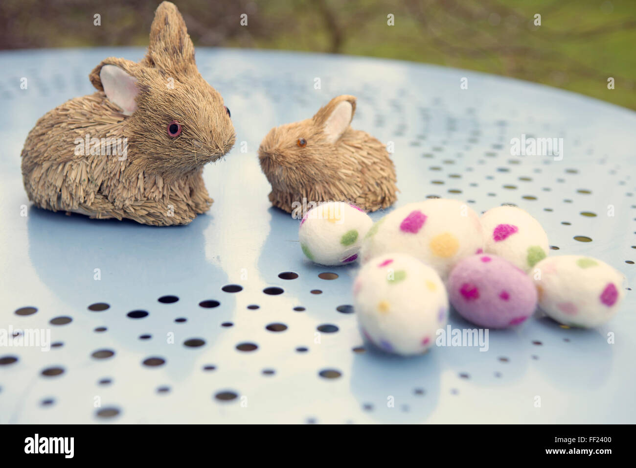 straw bunny with easter eggs on a blue table outdoors Stock Photo - Alamy