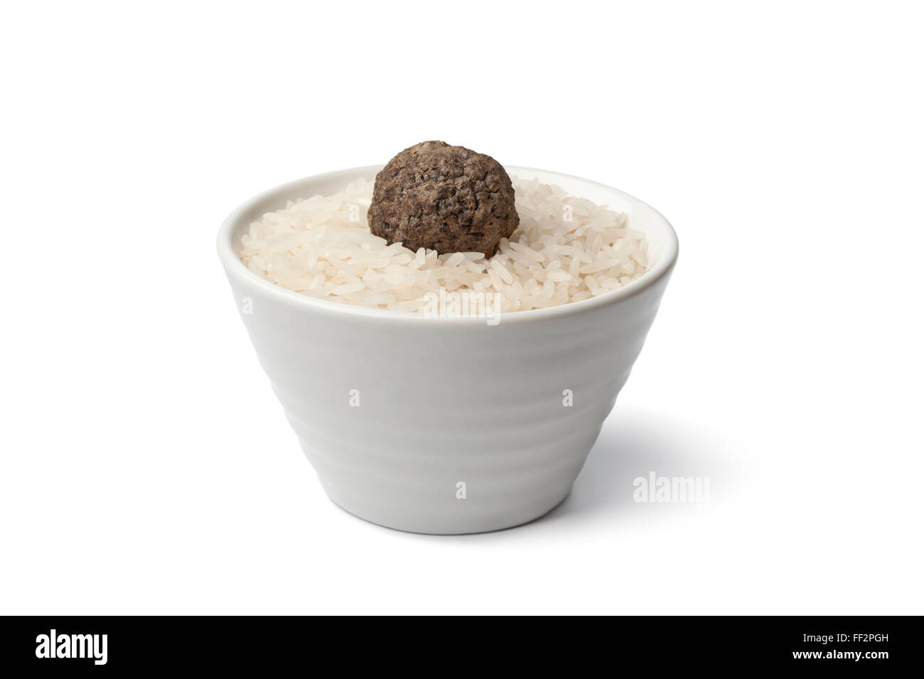 Cup of raw rice with fresh black winter truffle truffle on white ...