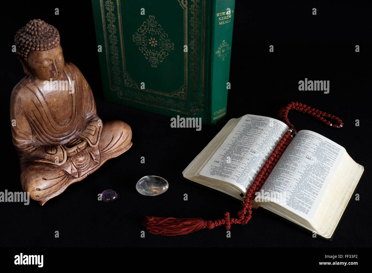 Wooden statue of Buddha with koran and holy bible Stock Photo - Alamy