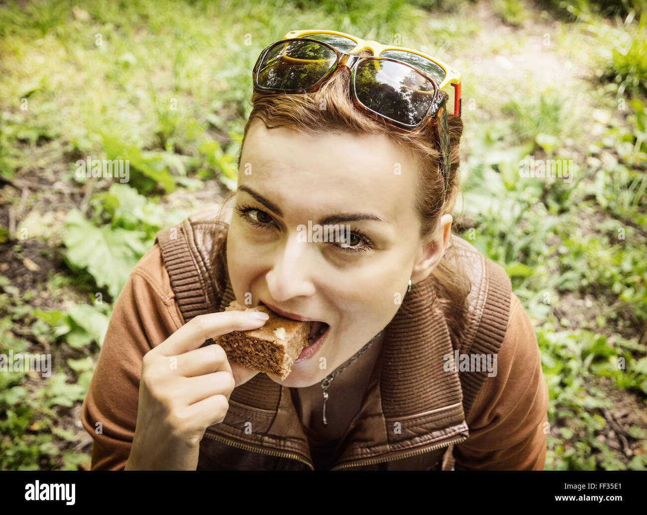Young caucasian woman is eating tasty gingerbread. Portrait in outdoor ...