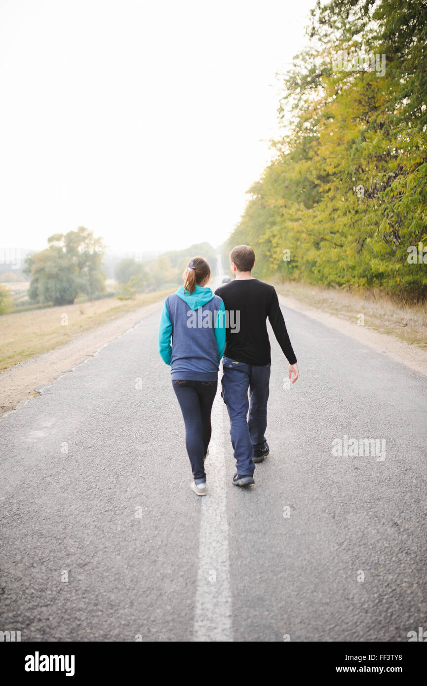 Young couple enjoying a walk on the road, holding hands Stock Photo - Alamy
