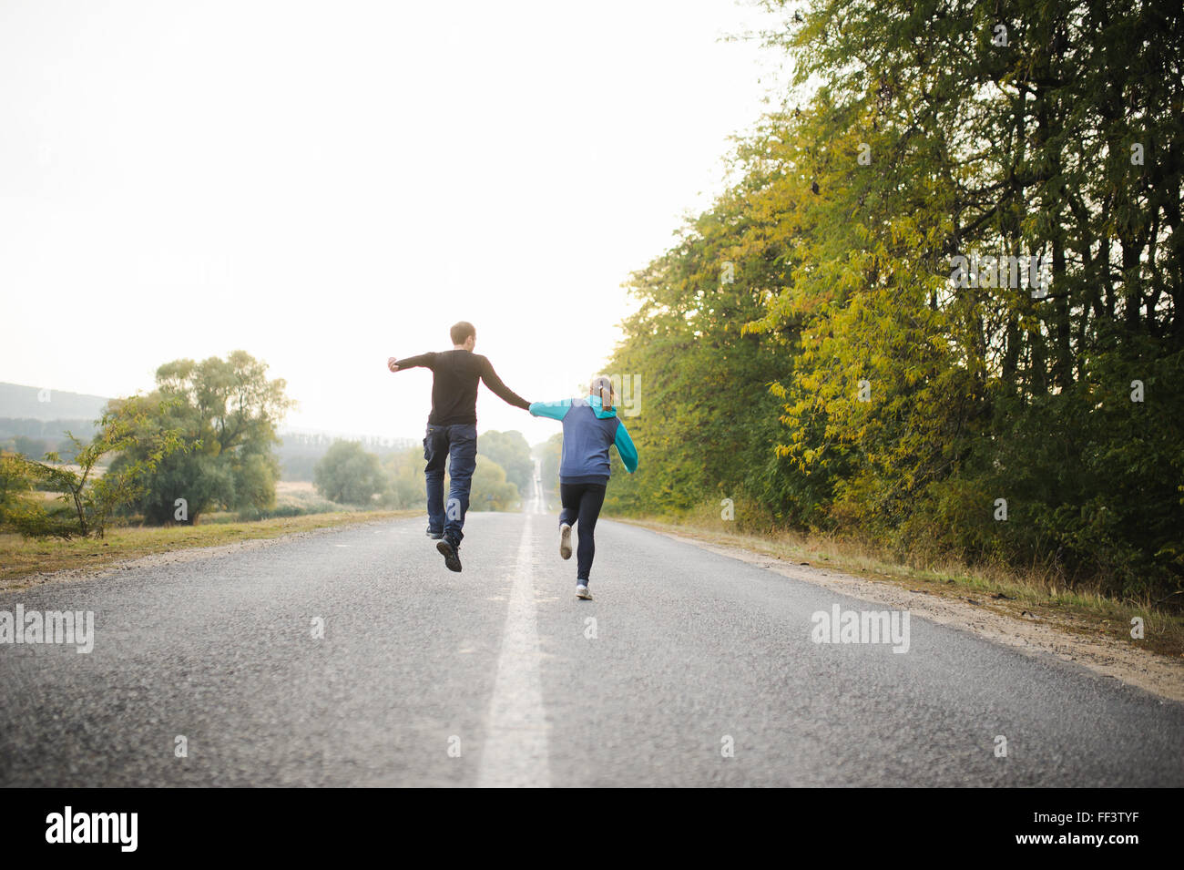 Young couple enjoying a walk on the road, holding hands Stock Photo - Alamy