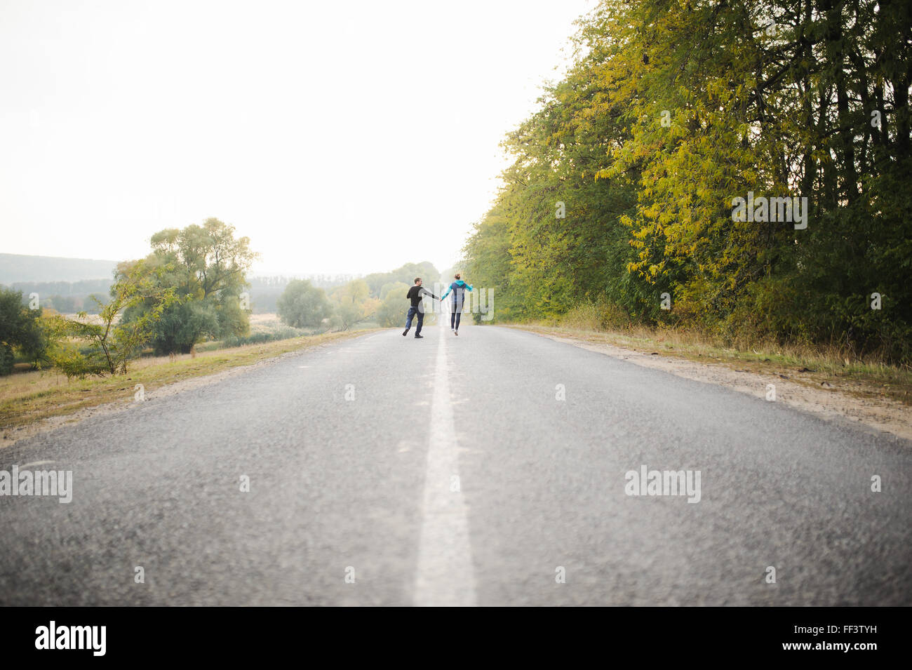 Young couple enjoying a walk on the road, holding hands Stock Photo - Alamy