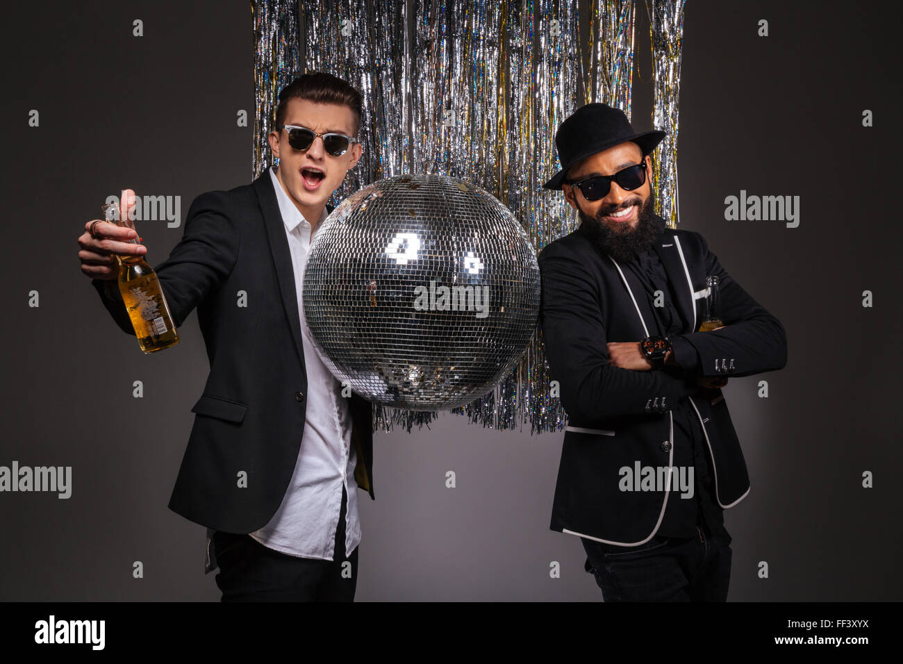 Two attractive young men standing and drinking beer on the party over ...