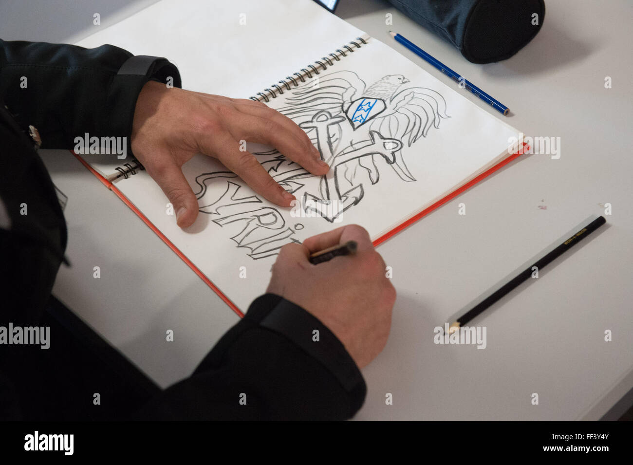 Security guard Orlando List draws a picture depicting the Syrian crest ...