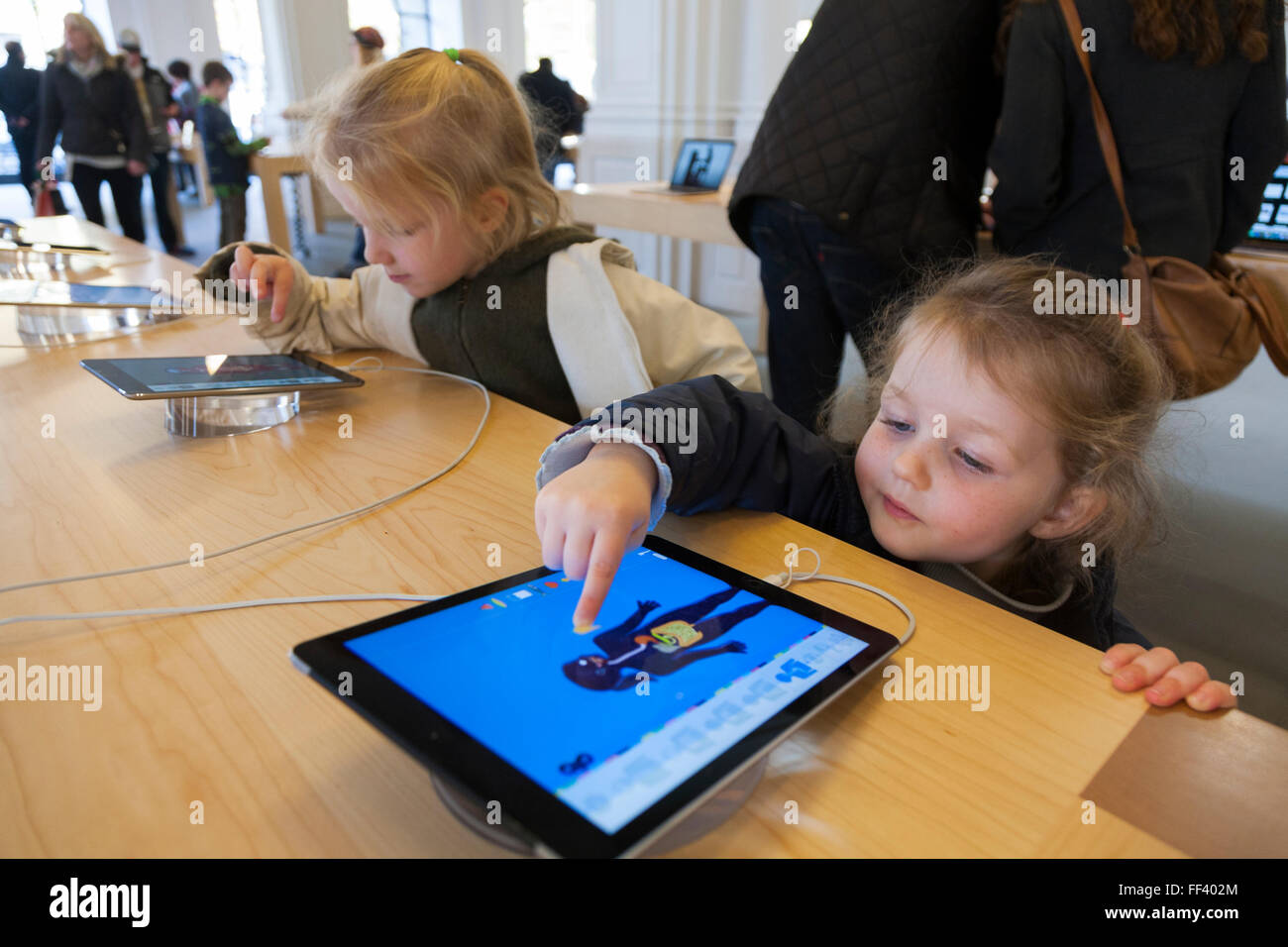 Three year old girl / child / kid, concentrating while using an iPad i ...