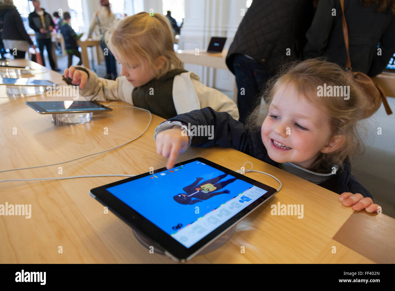 Three year old girl / child / kid, happy & smiling to be using an iPad ...