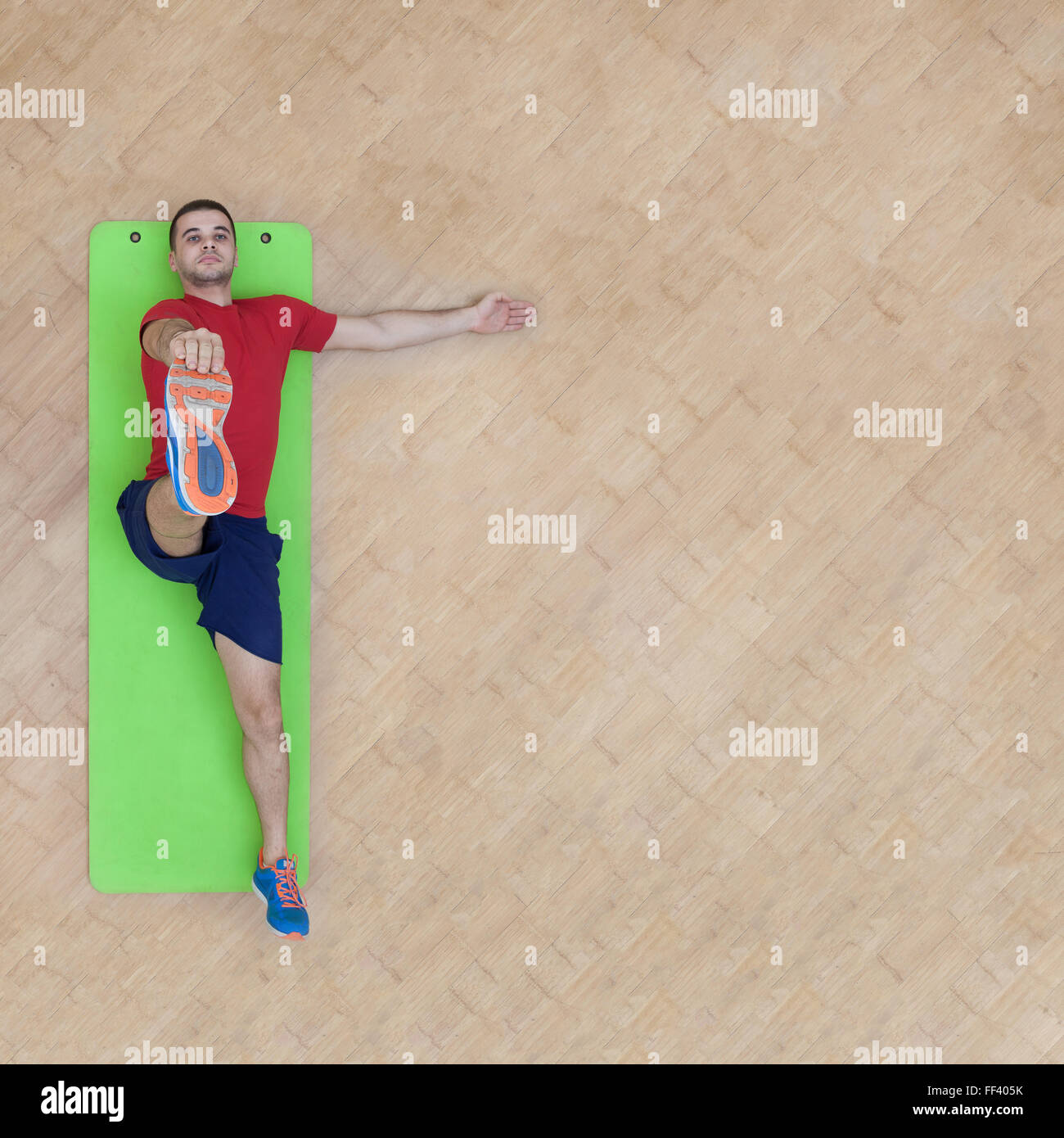 Fitness man doing stretching exercises on mat. Above image with copy ...