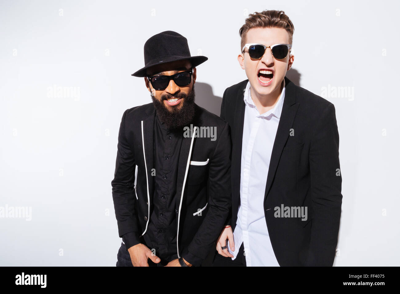 Two irritated modern young men in black suits shouting and looking at ...